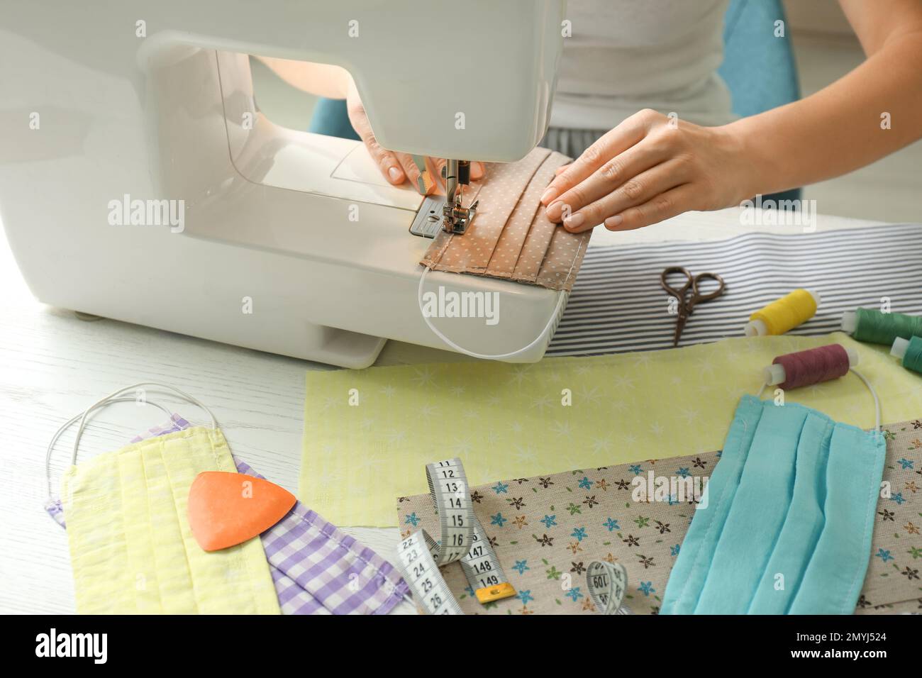 Woman sewing cloth mask with machine at table, closeup. Personal ...