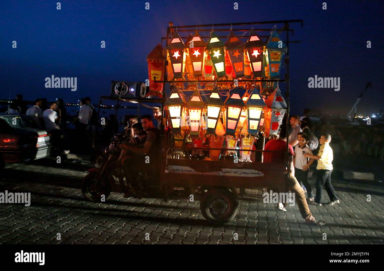 A Palestinian vendor rides a motorcycle cart with lighted traditional ...