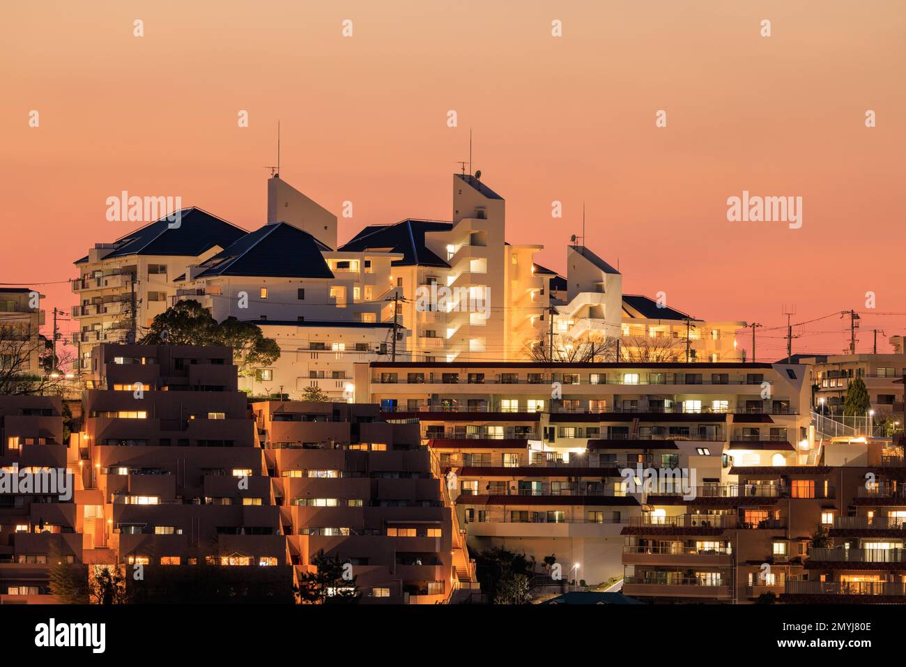 Orange sunset glow over lights in modern hillside apartments Stock ...