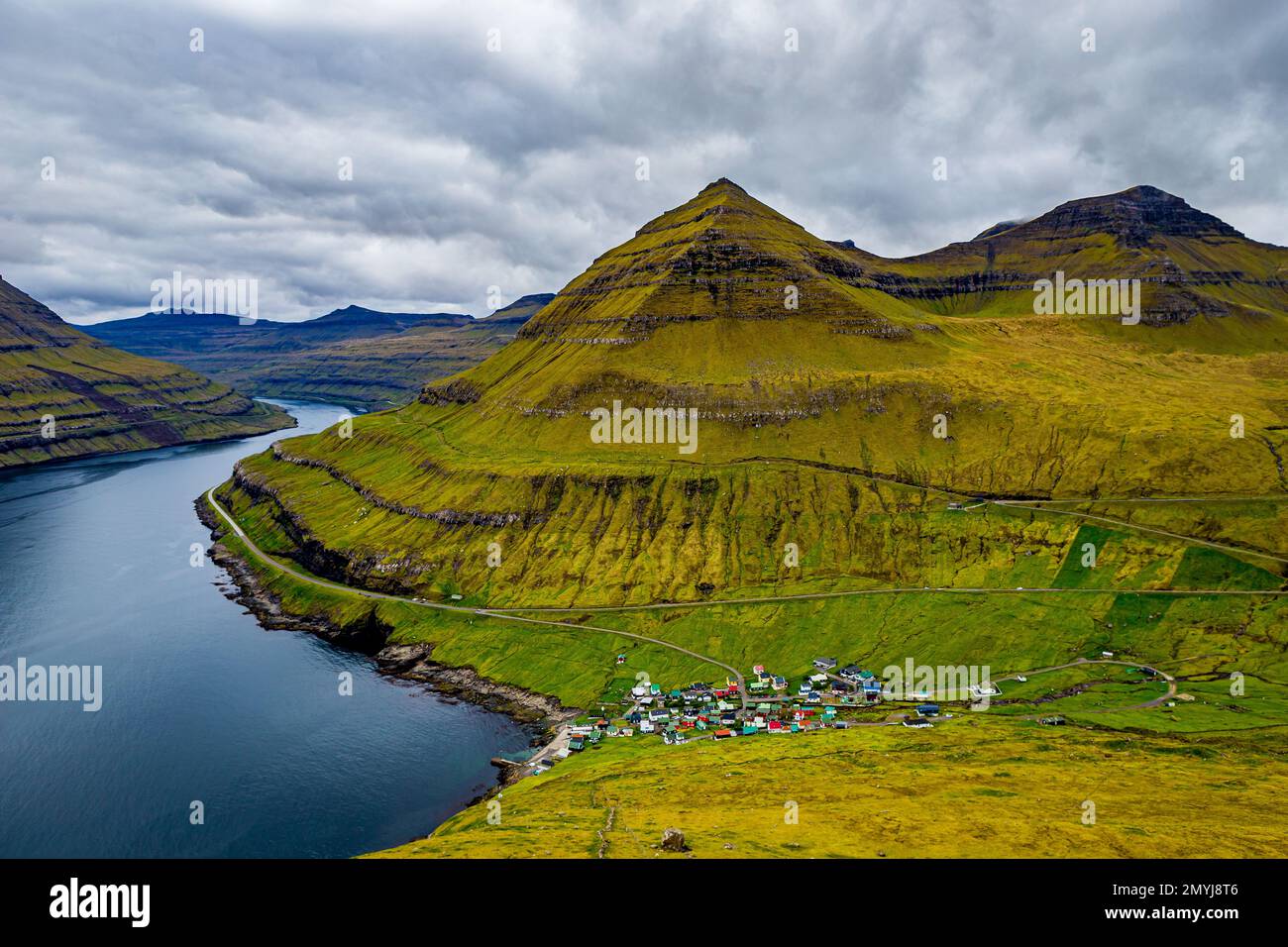 Village of Funningur nestled in a valley between coastal grassy ...