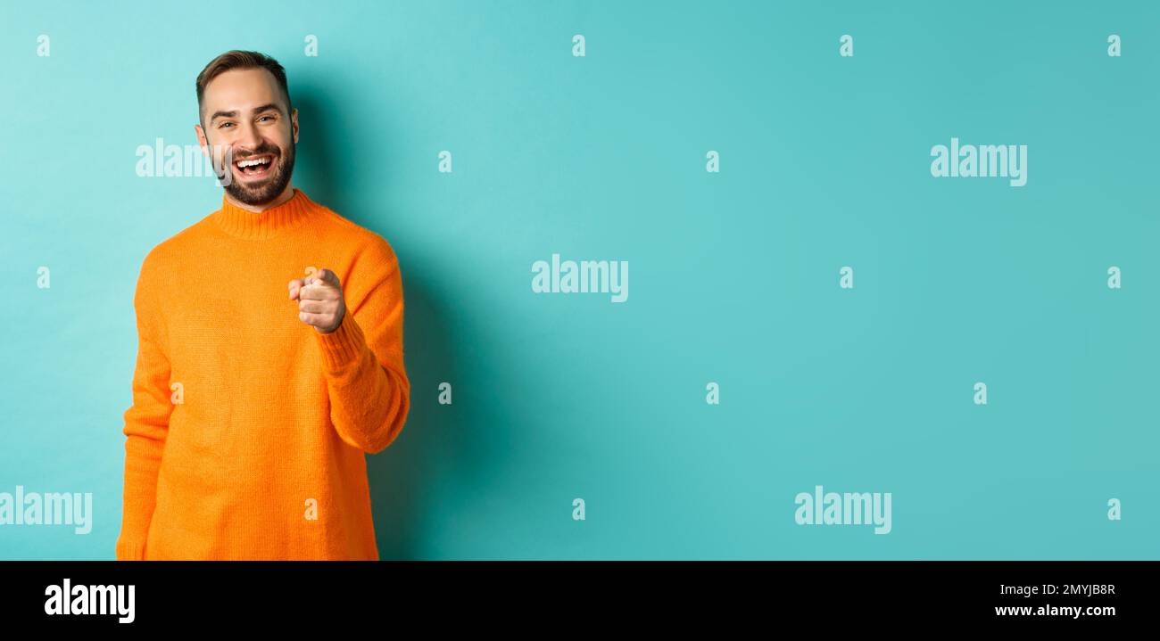 Handsome man laughing and pointing at camera, nodding in approval ...