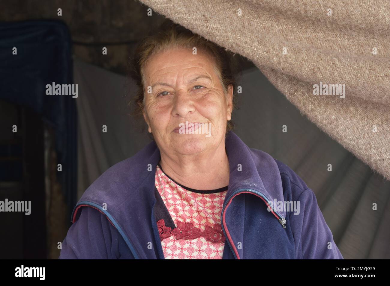 A smiling woman stands in the doorway of her village home in northern ...