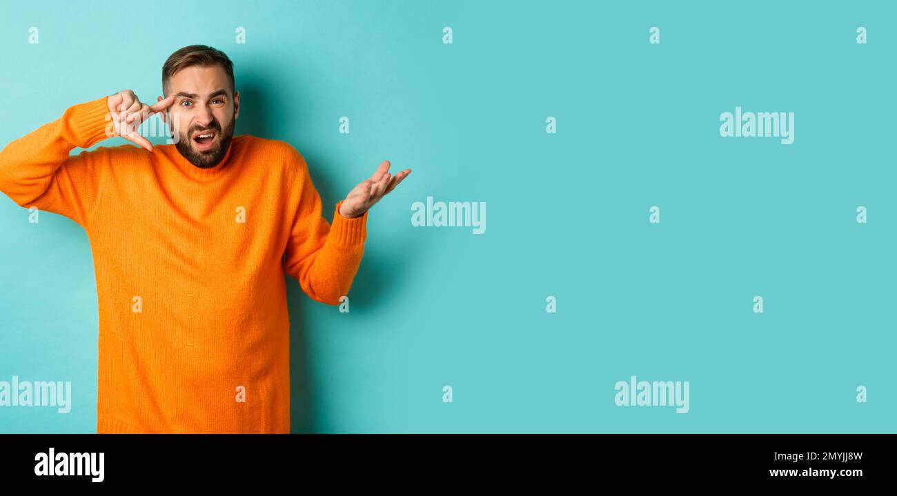 Angry man pointing at head, are you crazy gesture, scolding someone ...