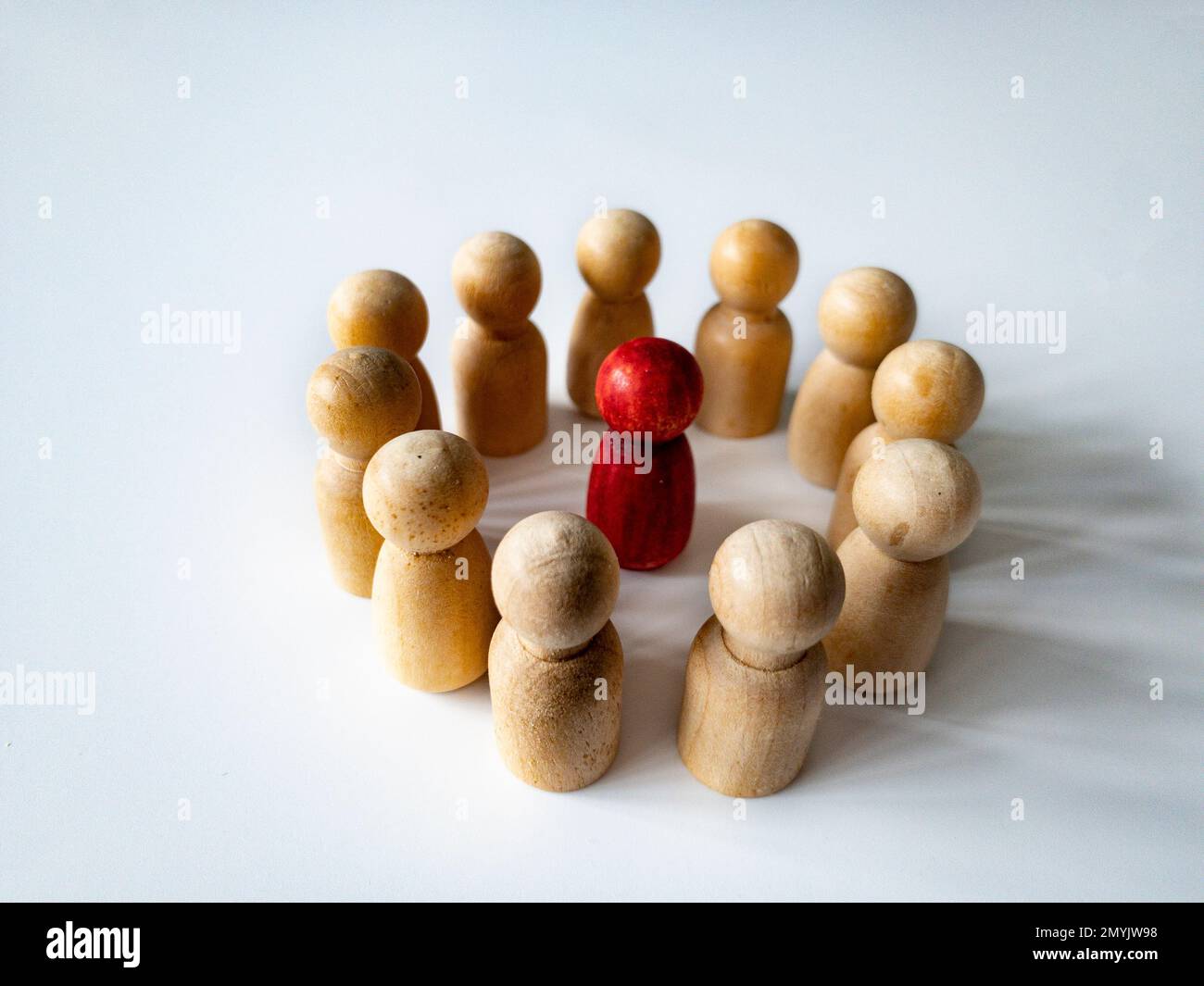 Red wooden doll figure surrounded by other doll figure on white ...