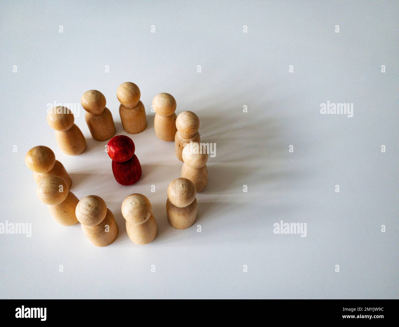 Red wooden doll figure surrounded by other doll figure on white ...