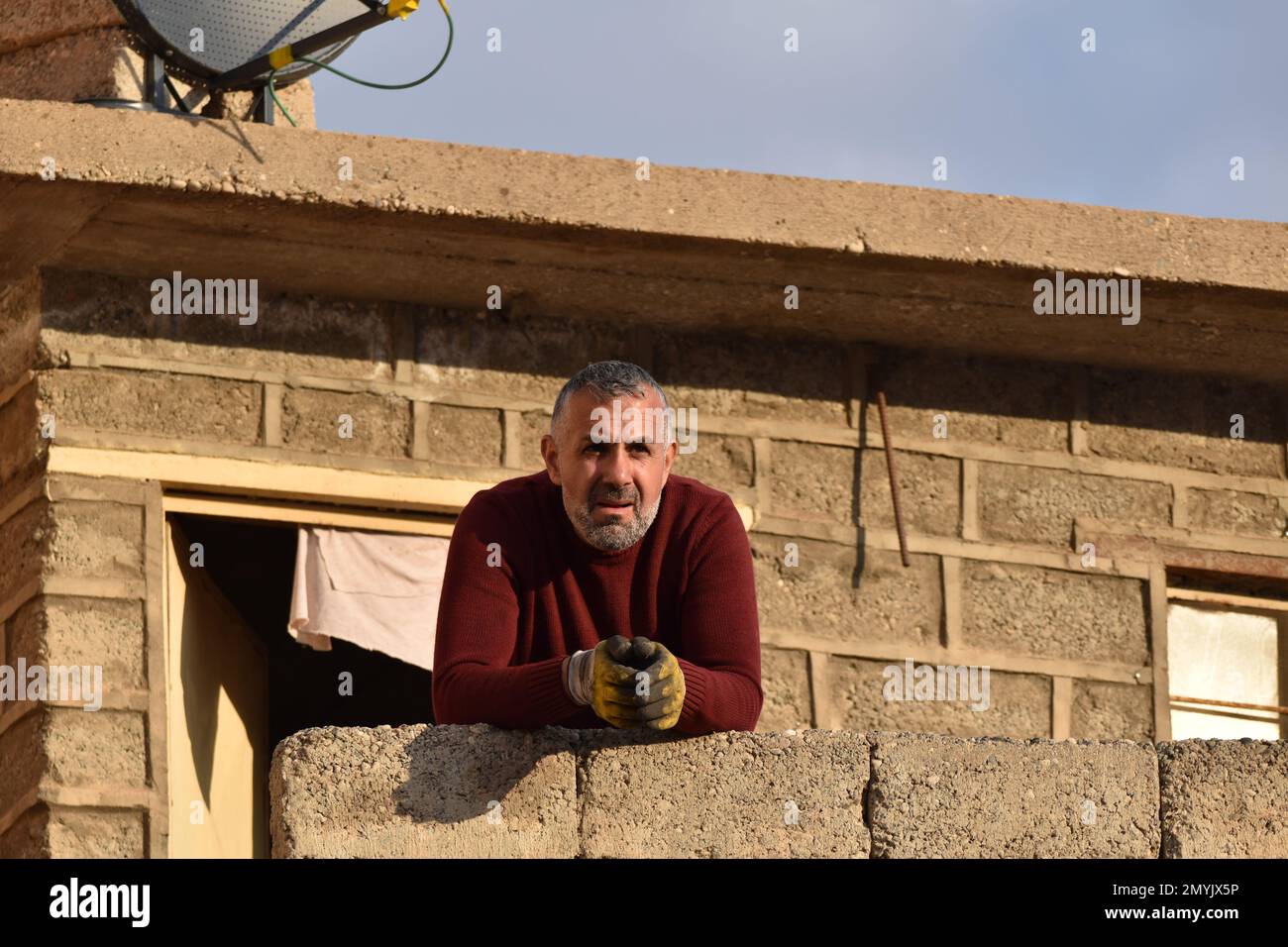 A Kurdish man leaning on the balcony of his home in a Northern Iraqi ...