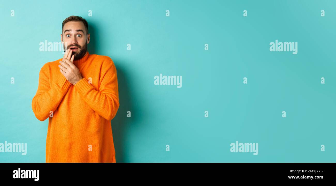 Scared and shocked guy looking at camera, standing in orange sweater ...