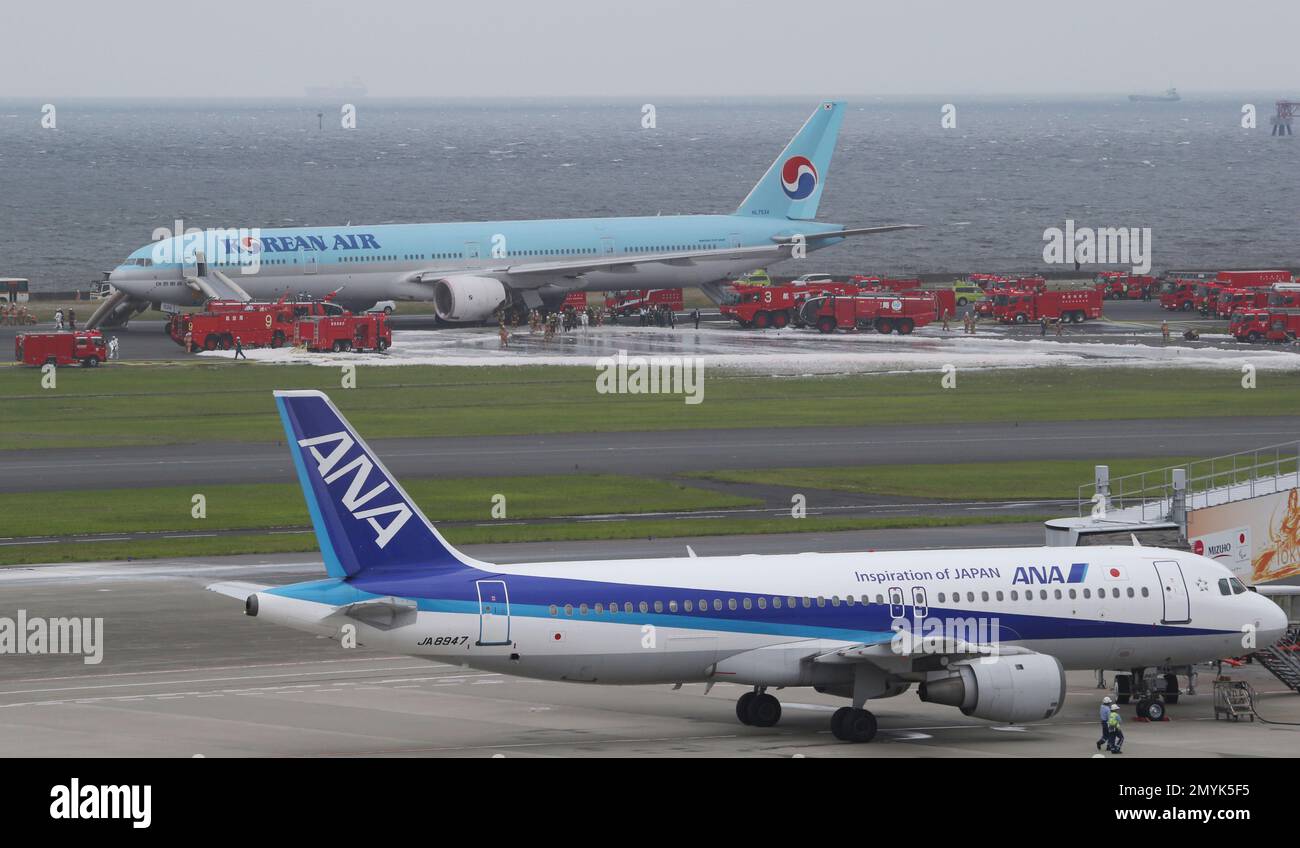Fire trucks park by a Korean Air jet sitting on the white foam-covered ...
