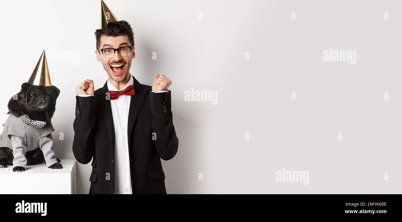 Cheerful young man shouting for joy, dog and owner wearing birthday ...