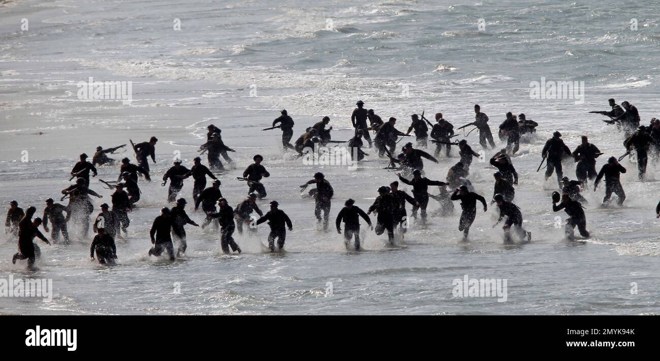 Actors perform on the beach during filming a scene for the film ...
