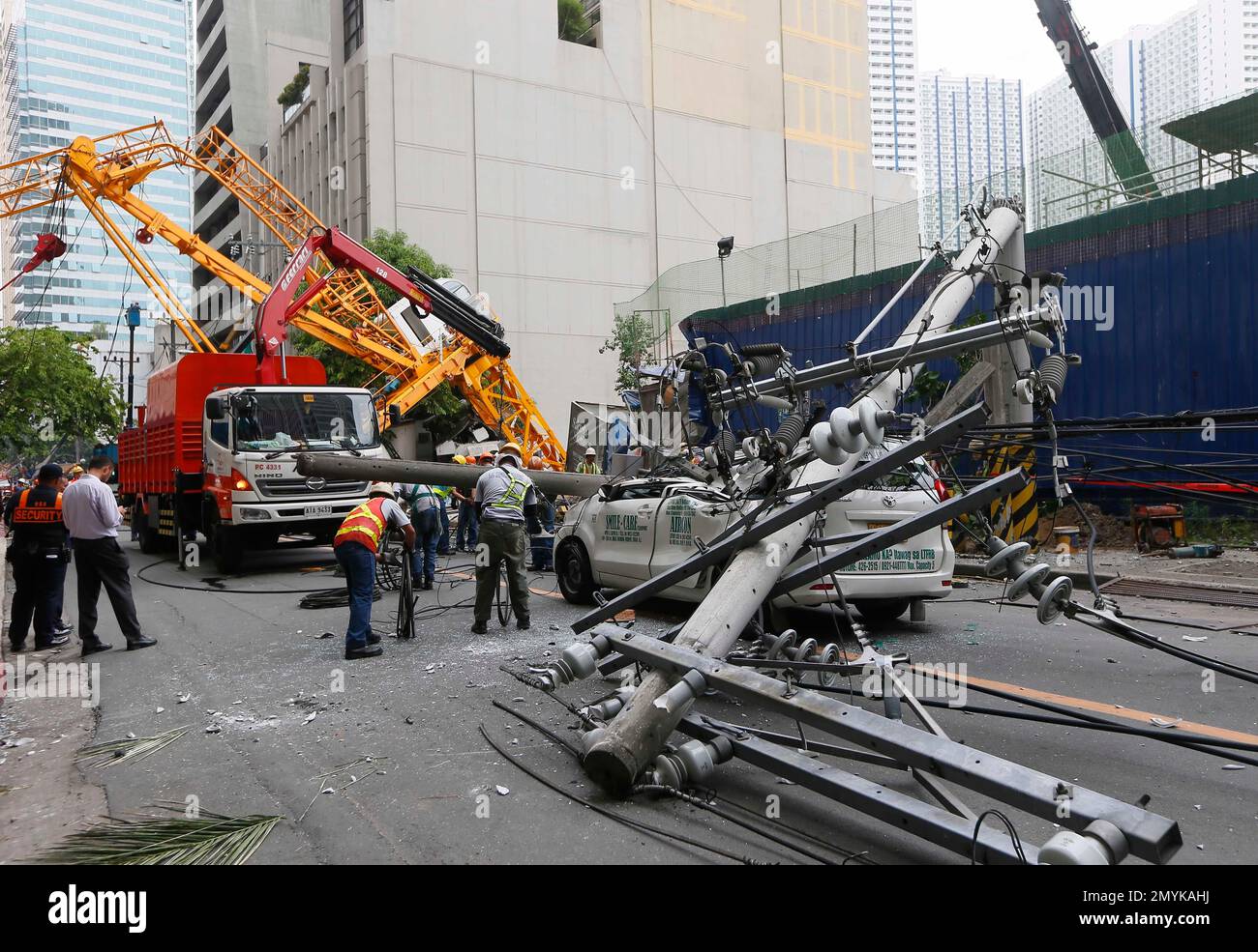 Workers gather near a construction crane which collapsed at a ...
