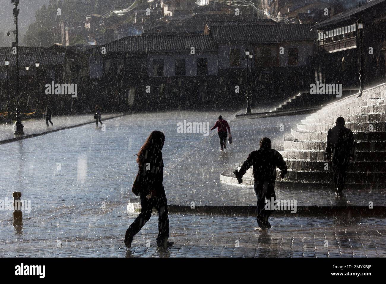 People walk under a heavy rain downtown in Cusco, Peru, Wednesday, May ...