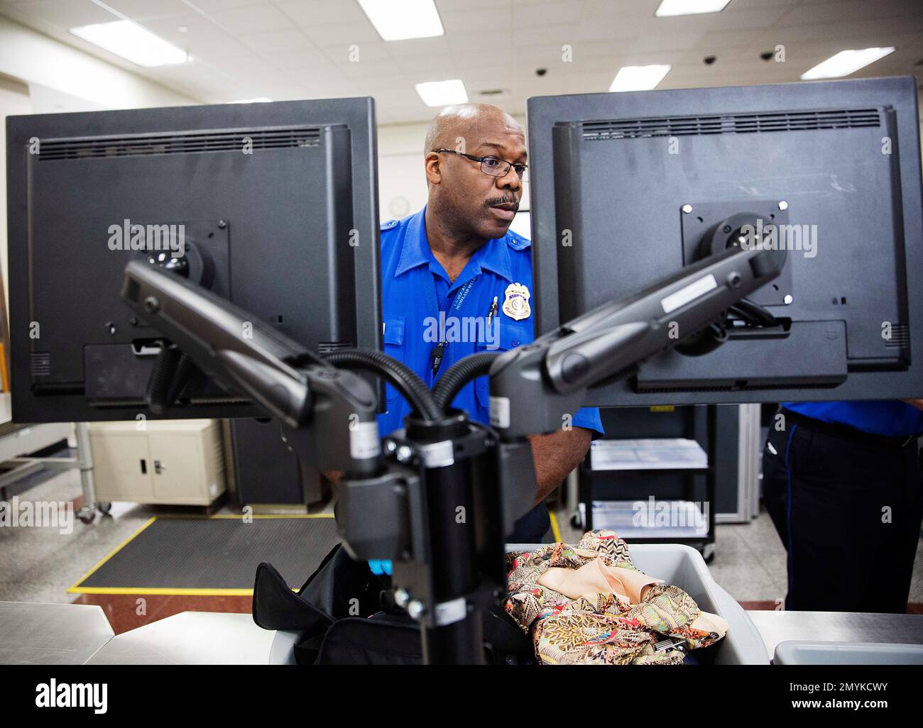 TSA officer Jerry Vernon looks at a screen while checking a bag at a ...