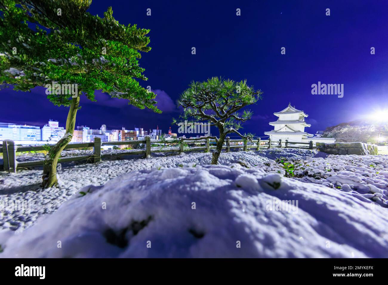 Snow covered landscape with Japanese castle and modern city at night ...