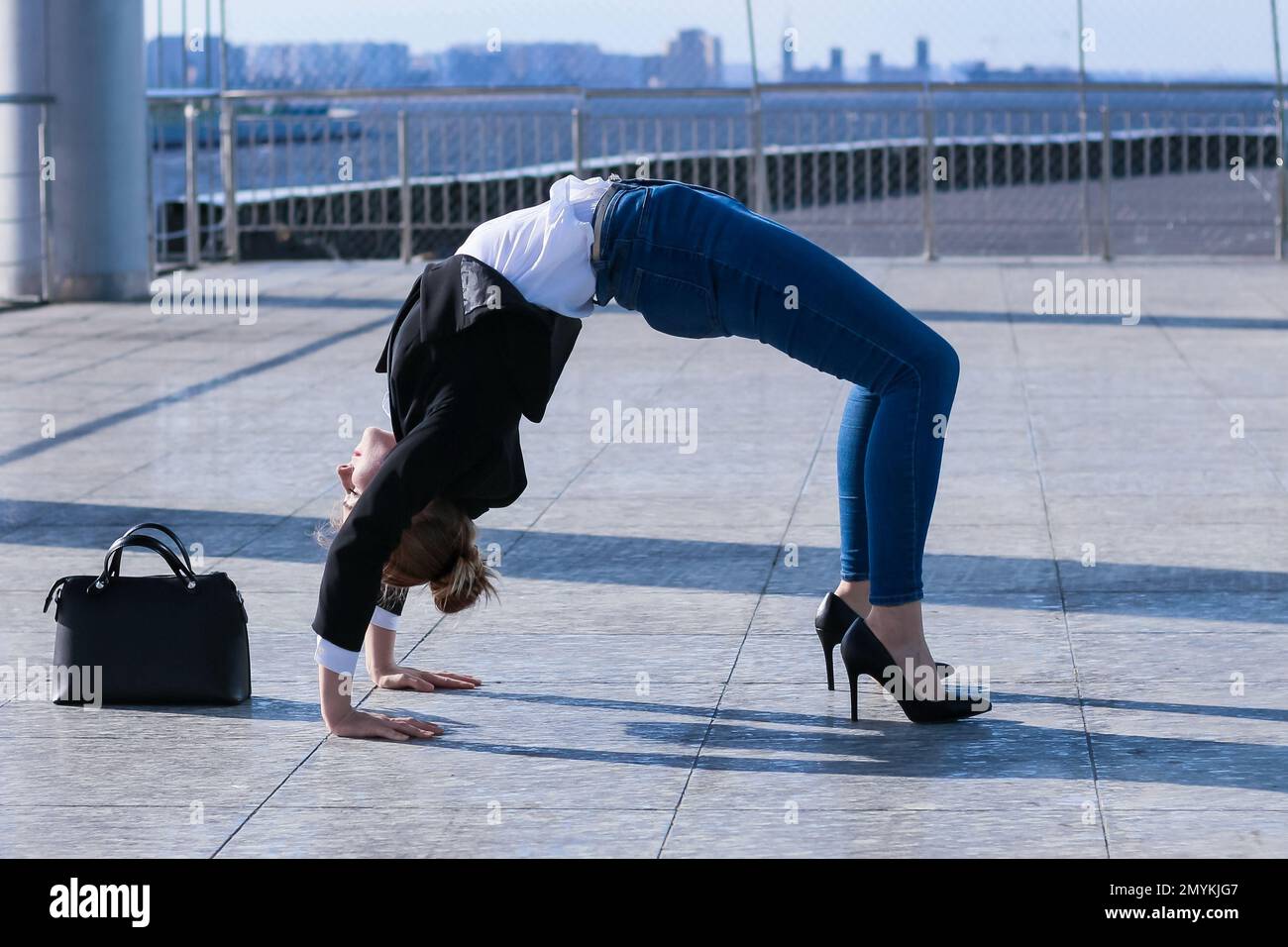 slender young woman in black jacket and jeans practice yoga asana ...