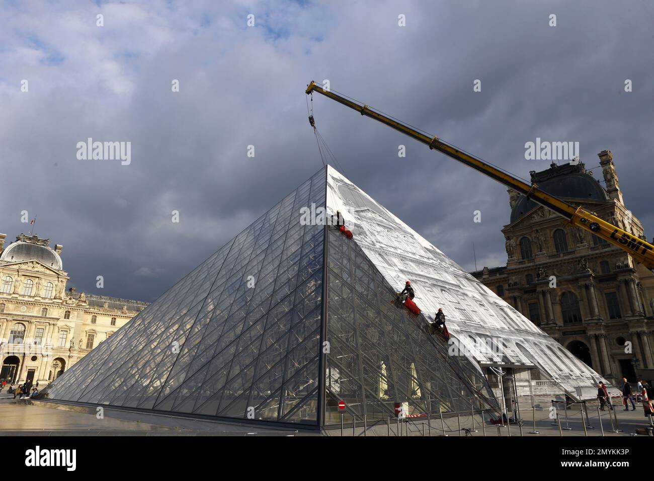 Rope access technicians paste a giant picture on the Louvre Pyramid as ...