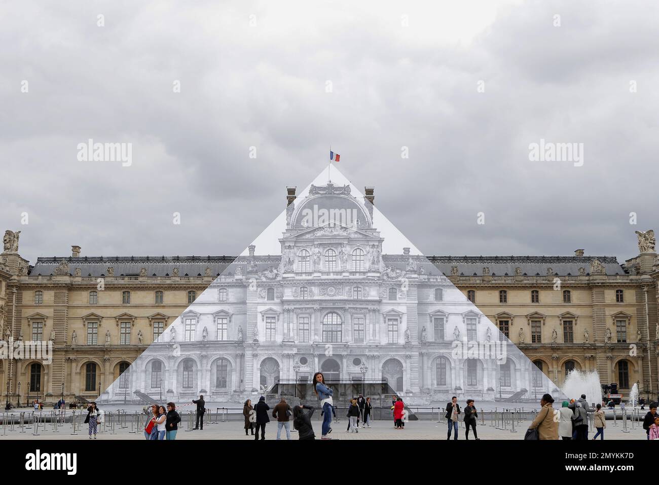 Tourists walk around theJR project at the Louvre Pyramid in Paris ...