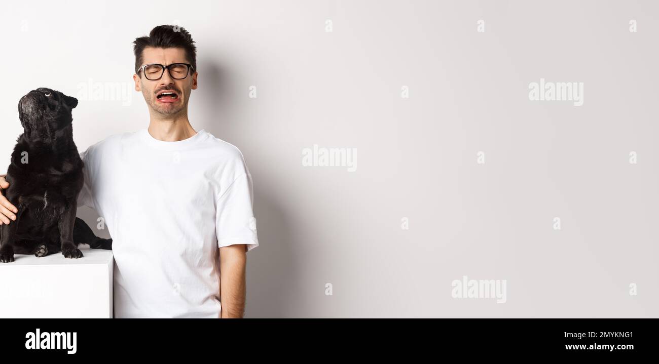 Image of sad crying man hugging his cute black pug, dog looking curious ...