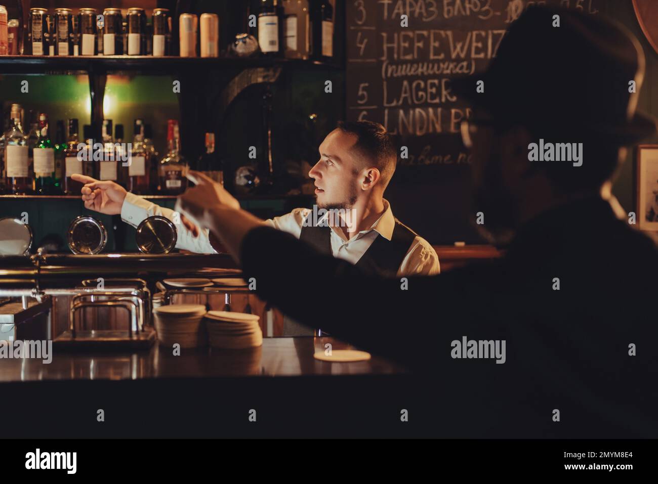 man orders an alcoholic drink from a bartender in a bar Stock Photo - Alamy