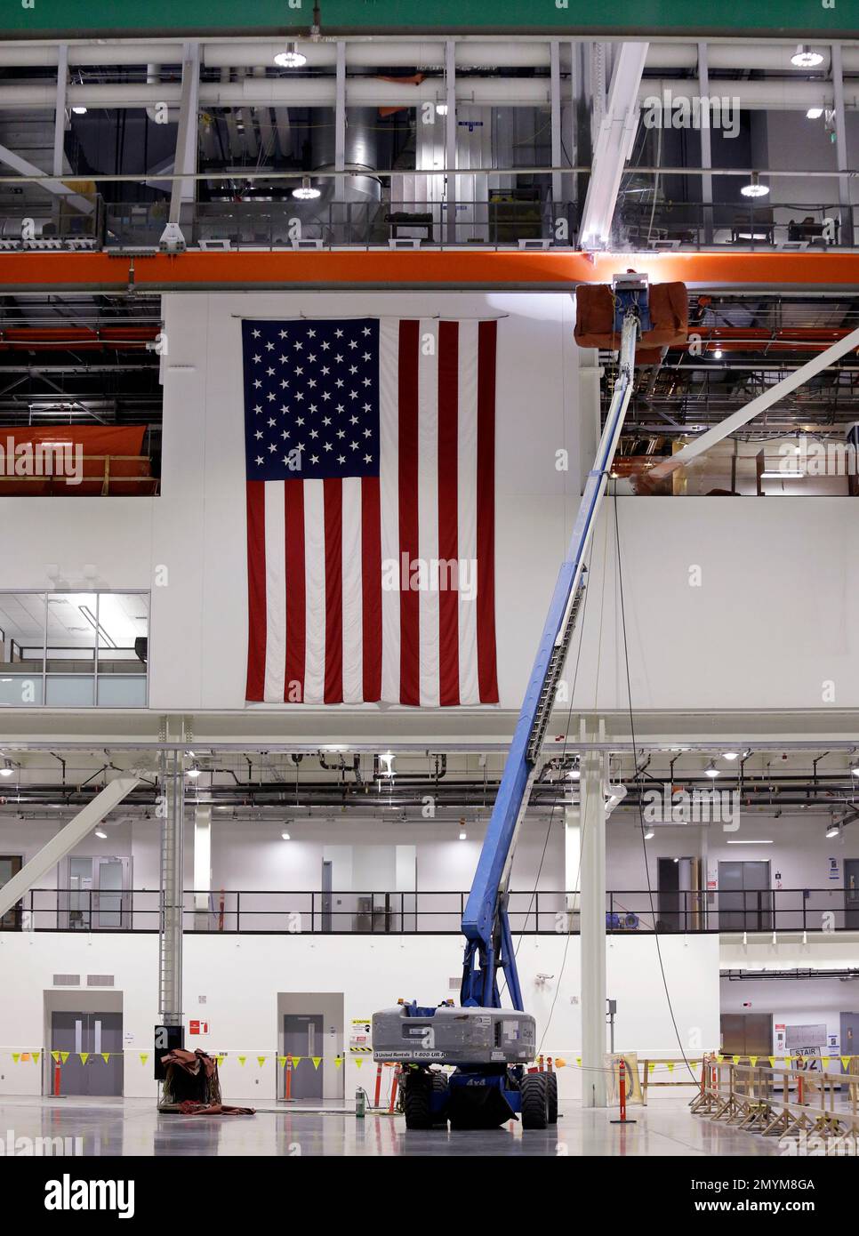 A worker is suspended high above the floor of the new Boeing 777X ...