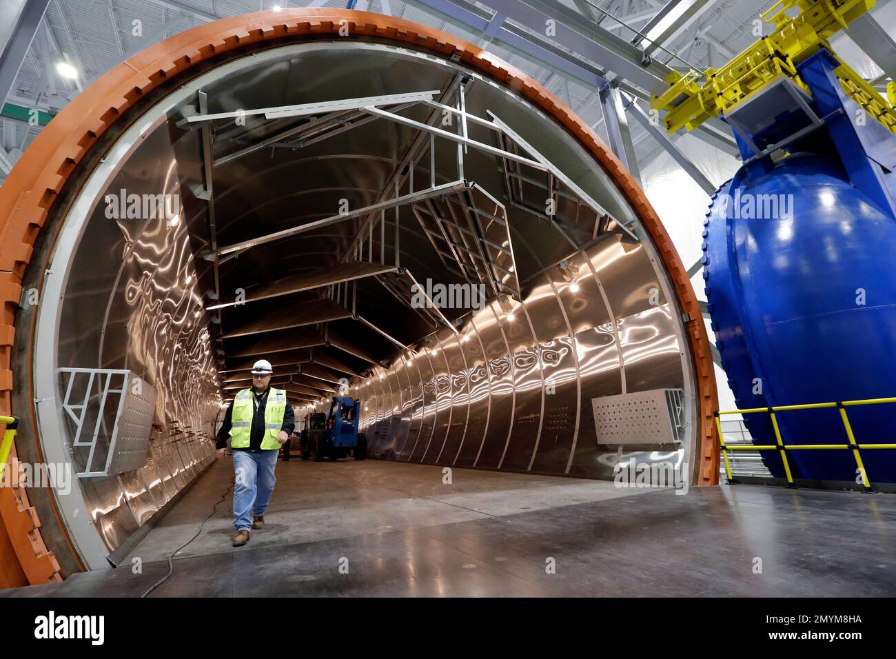 A worker walks out of a massive autoclave that will be used to bake ...