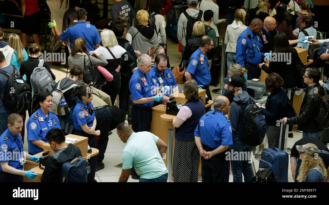 TSA agents check passenger boarding passes and identification at a ...
