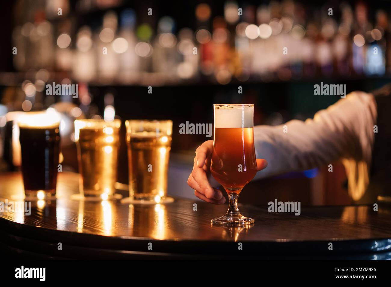 bartender hands a glass of tulip frothy draft beer to bar counter Stock ...