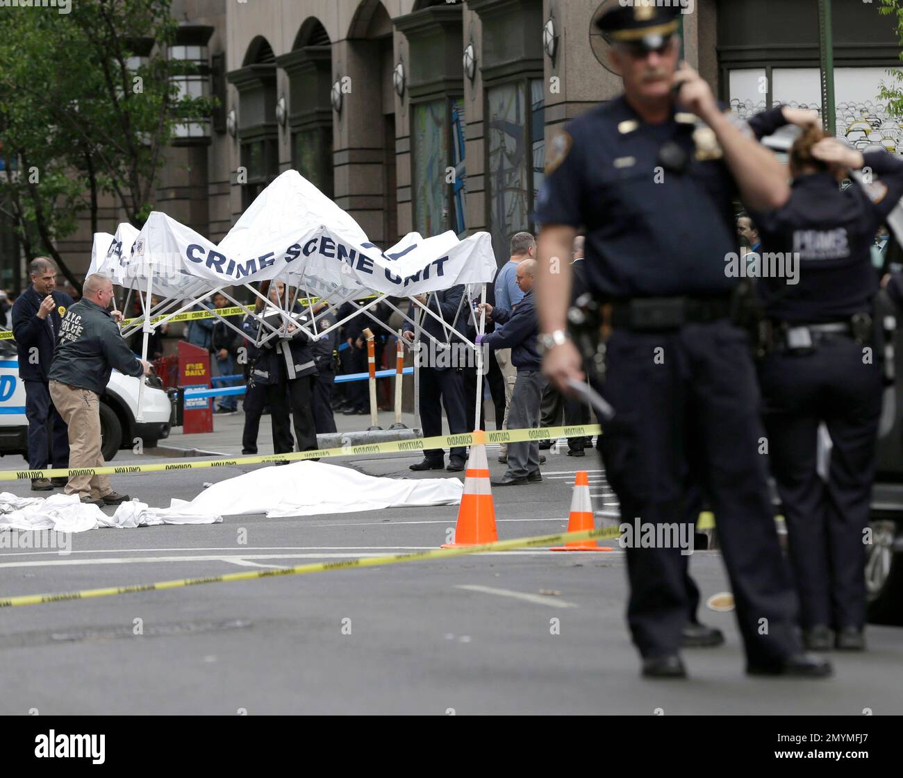 Emergency officials set-up a crime scene tent over a covered body ...