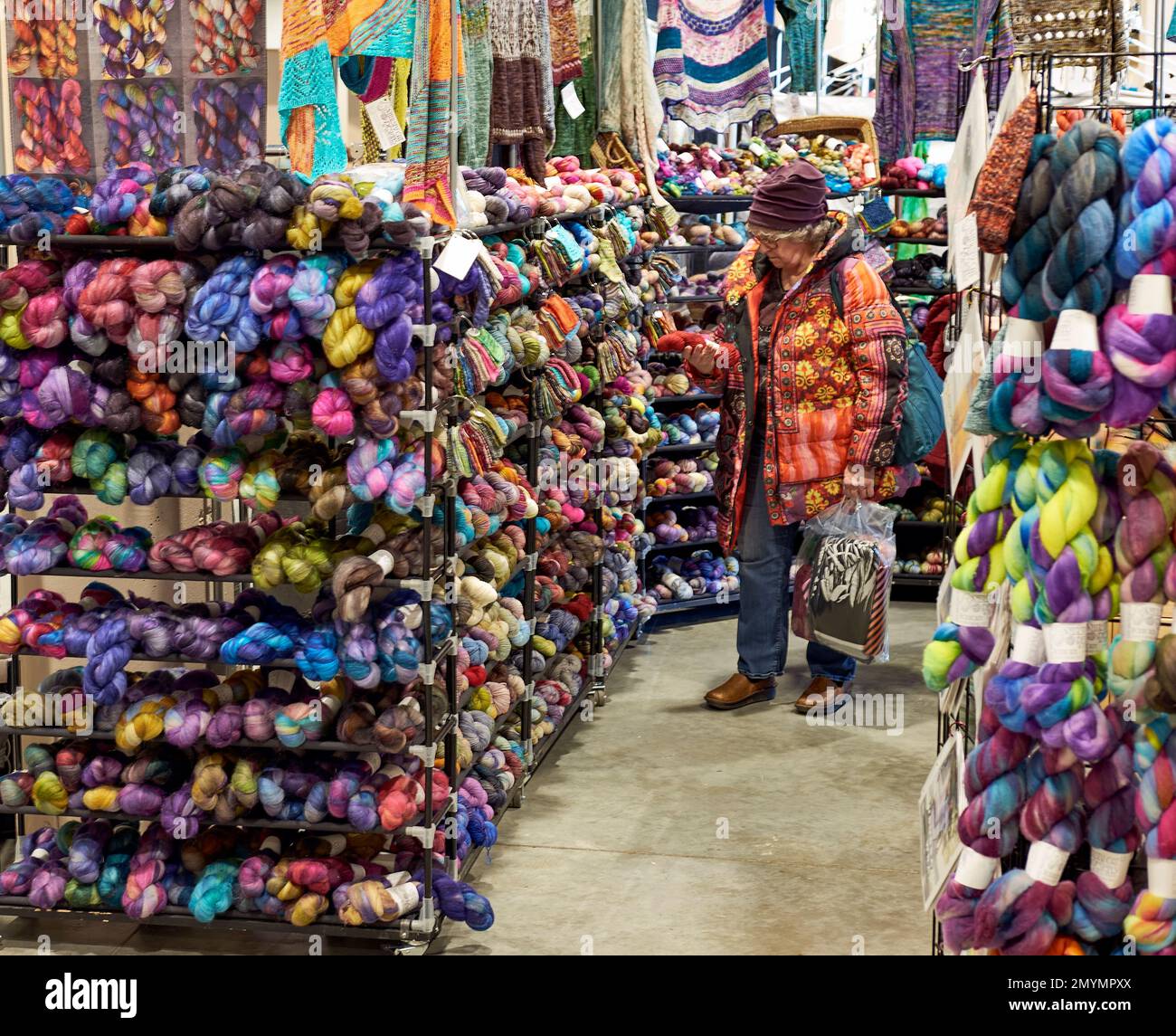 A crafter chooses a multicolored wool yarn from the many skeins on a ...