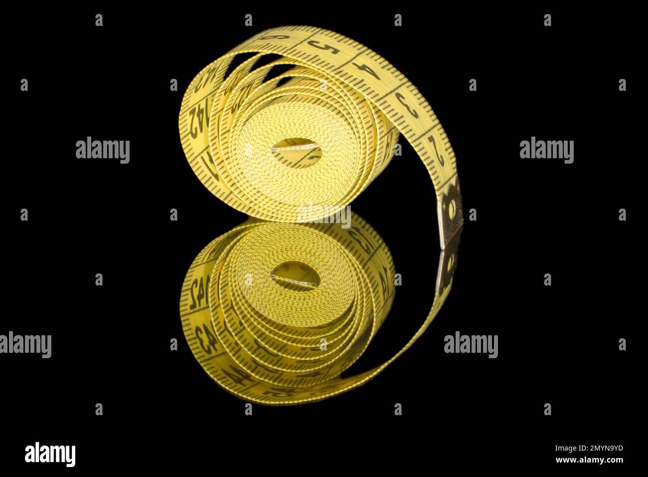 Rolled up yellow tape measure, studio photography with black background ...