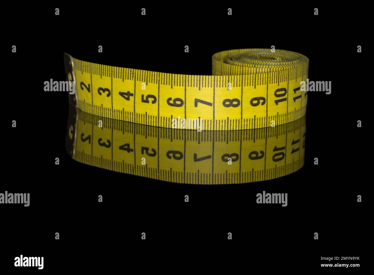 Rolled up yellow tape measure, studio photography with black background ...