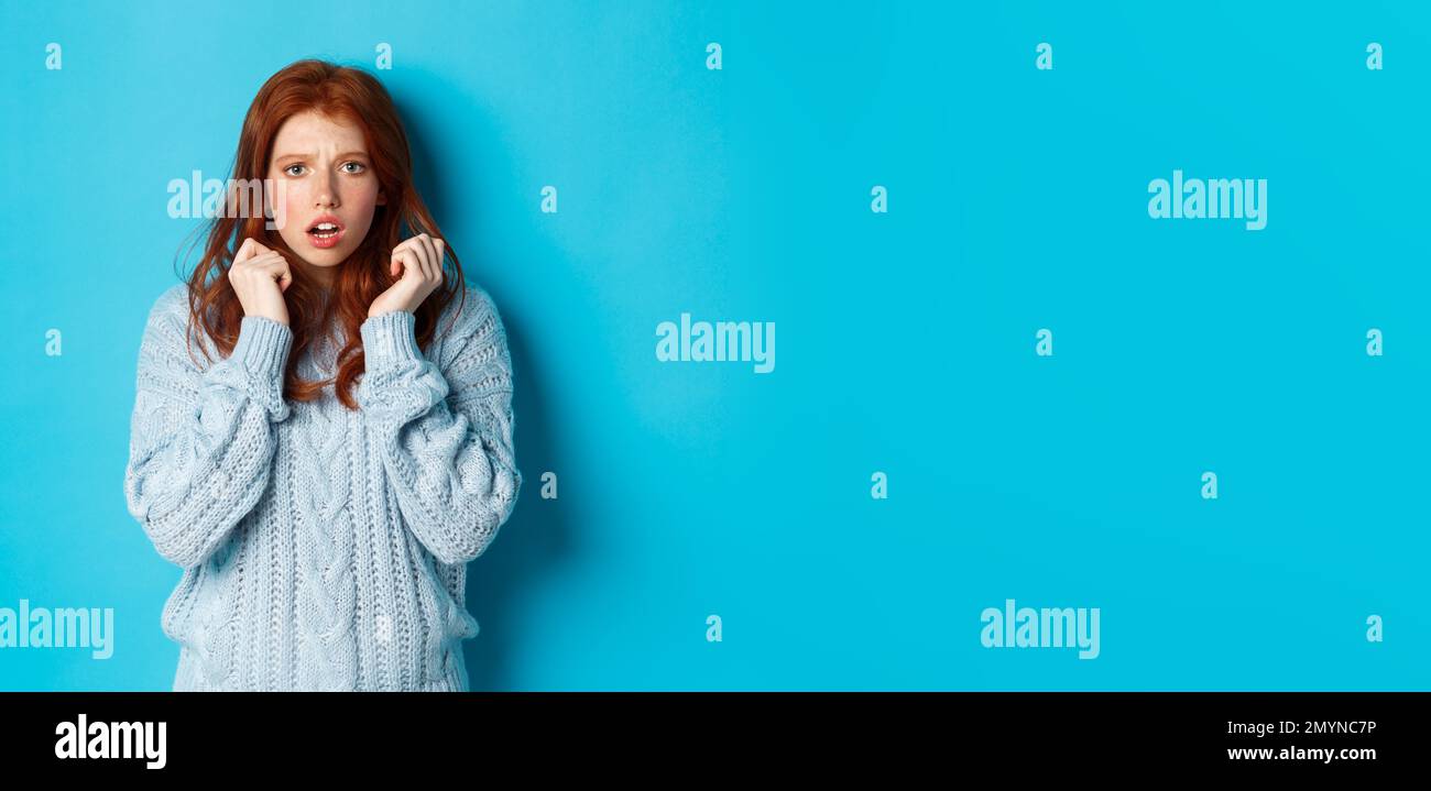 Image of scared teenage girl with red hair, jumping startled and ...