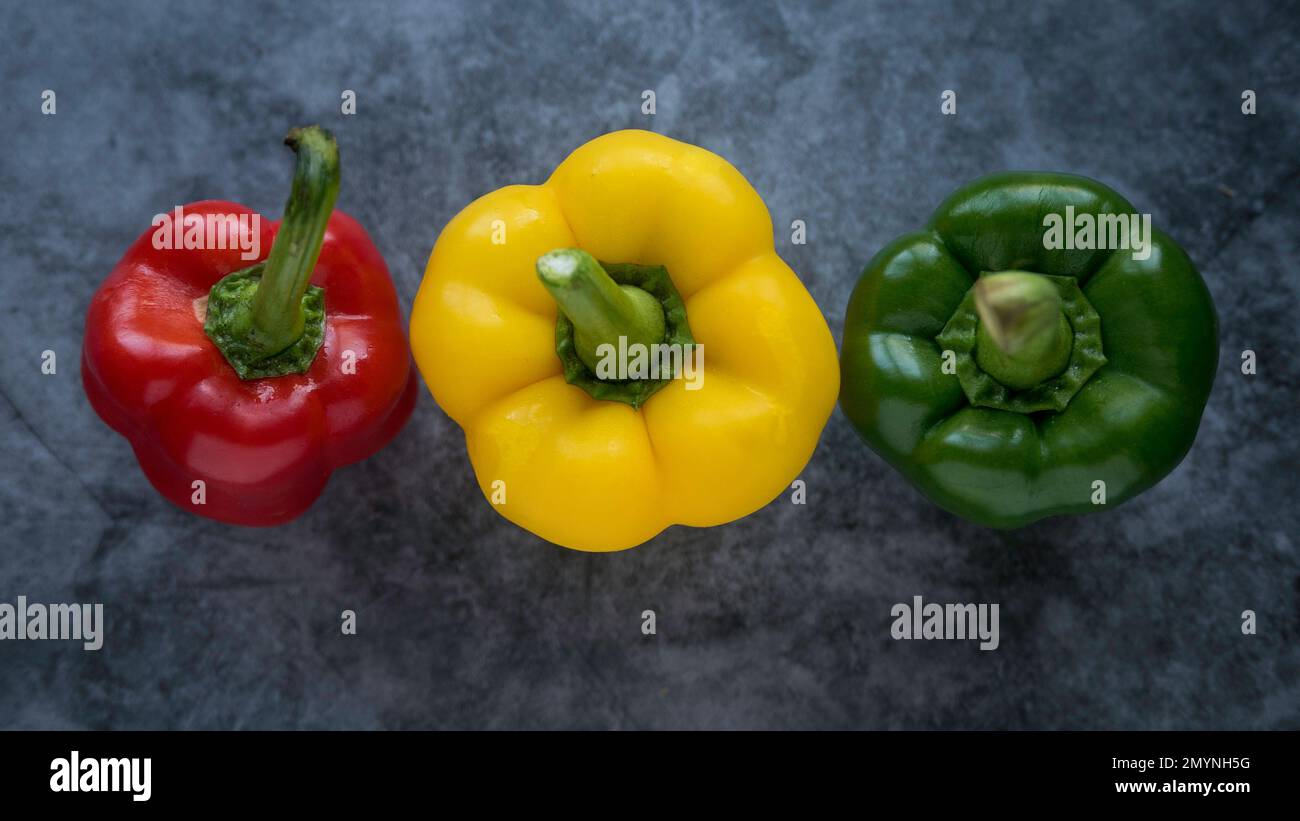 Three different colored of sweet bell peppers isolated on dark ...