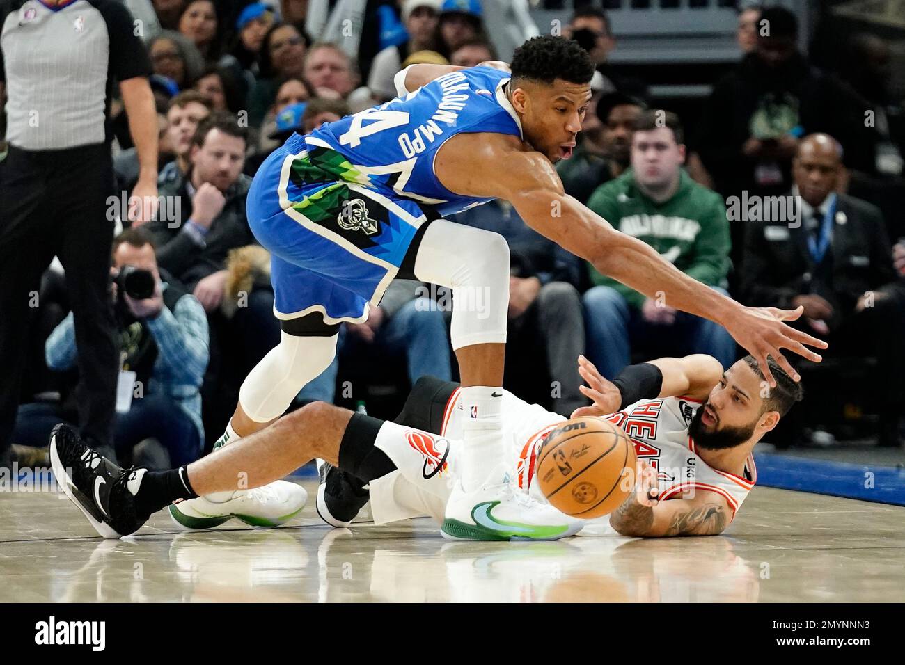 Miami Heat's Caleb Martin, bottom, passes the ball around Milwaukee ...