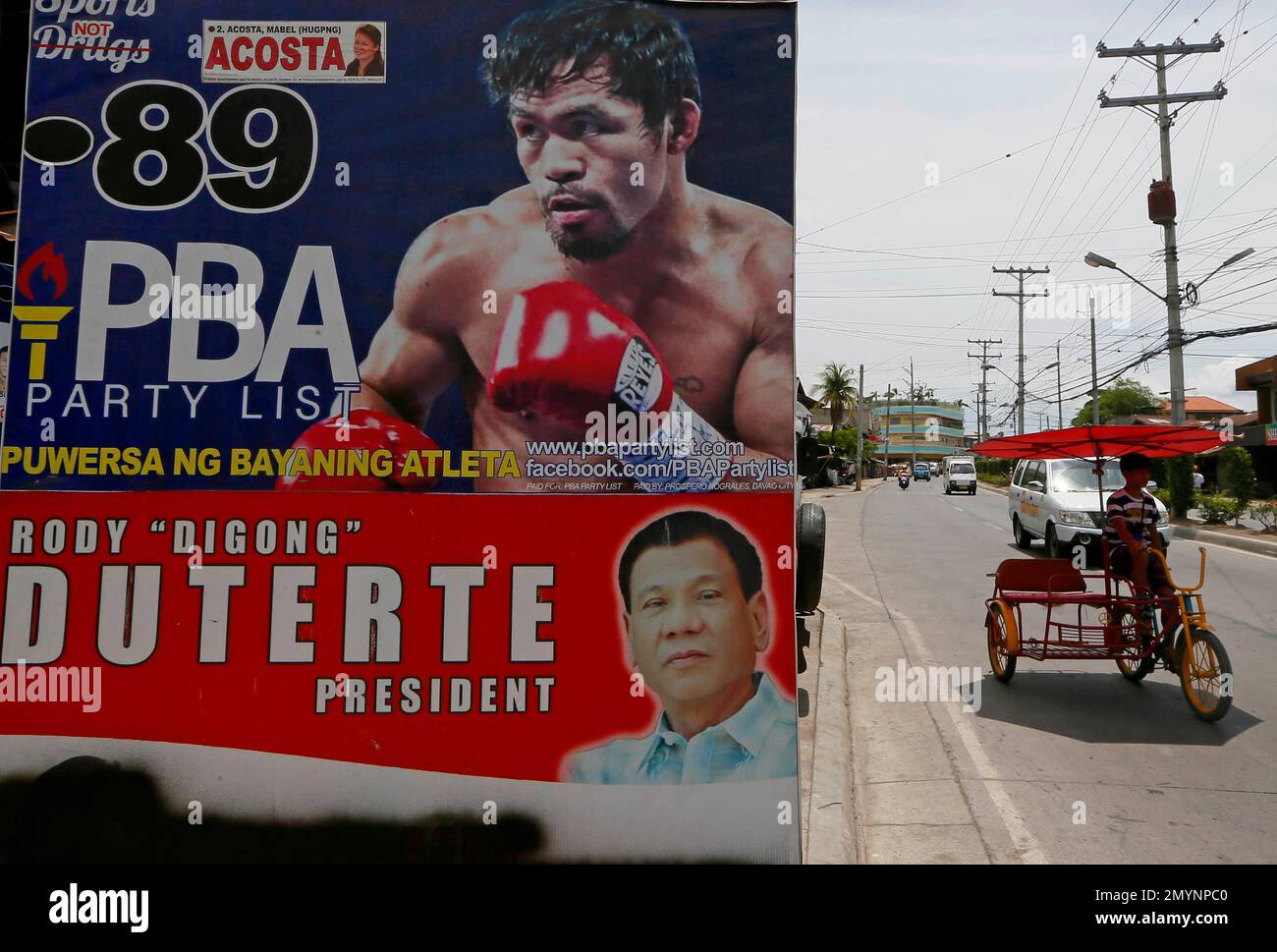 A man pedals his tricycle past a campaign poster of Filipino boxing ...