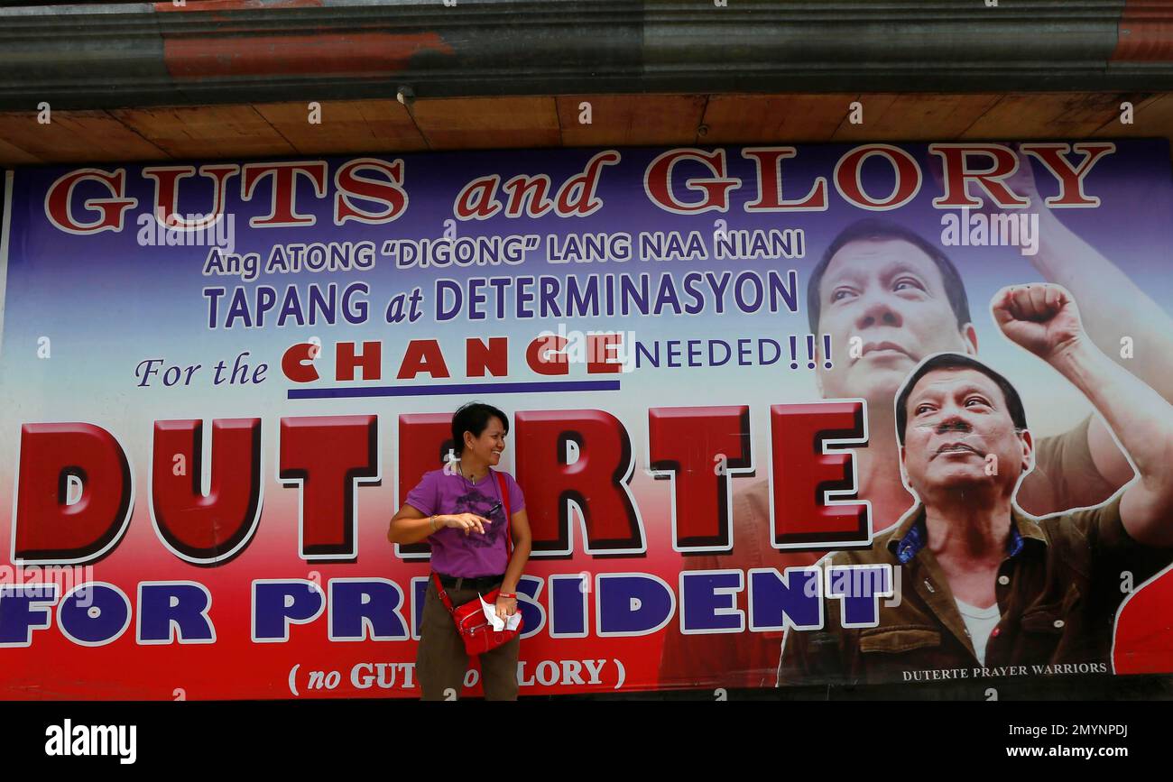 A resident takes stays in the shade behind a campaign billboard of ...