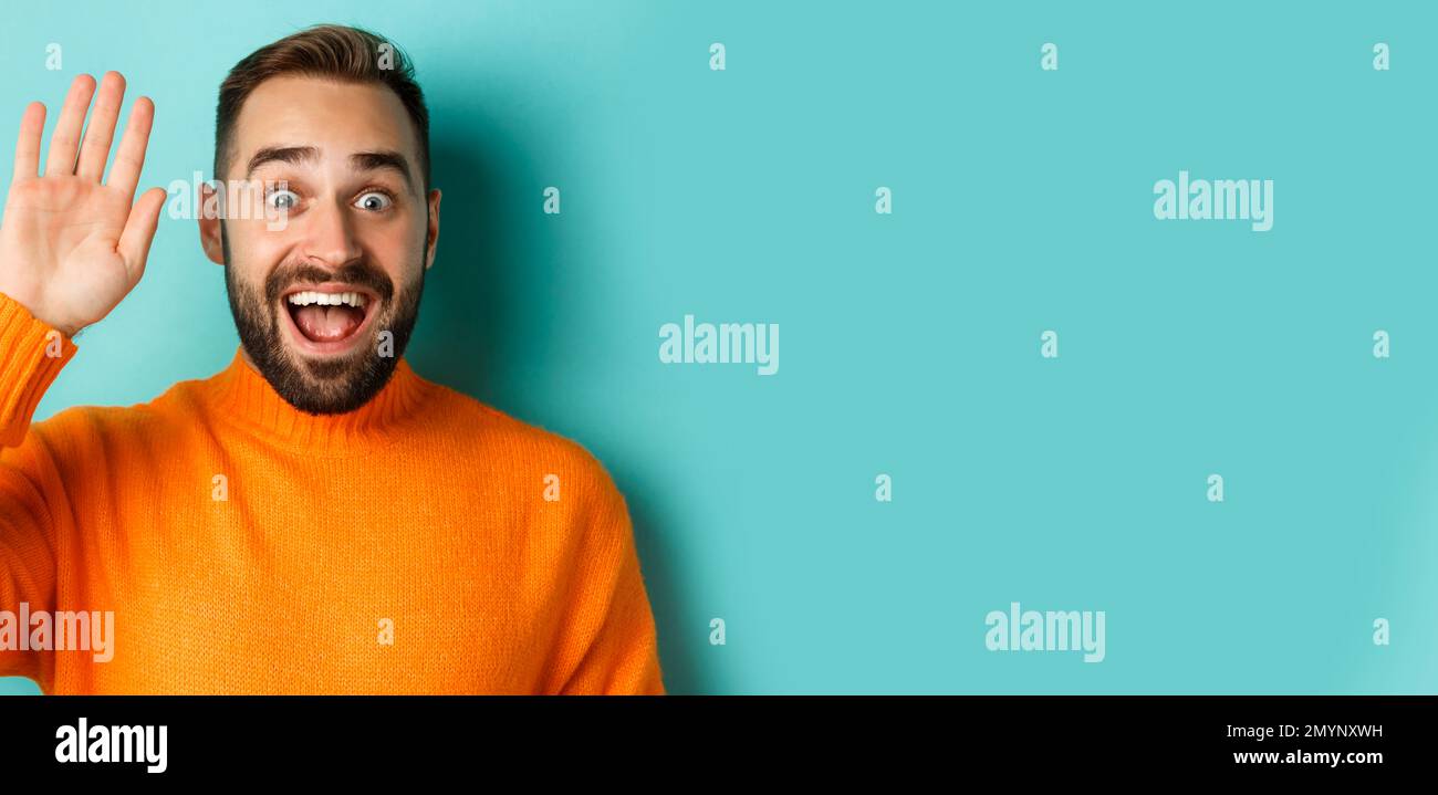 Handsome man waving hand to say hello, giving high five, standing over ...