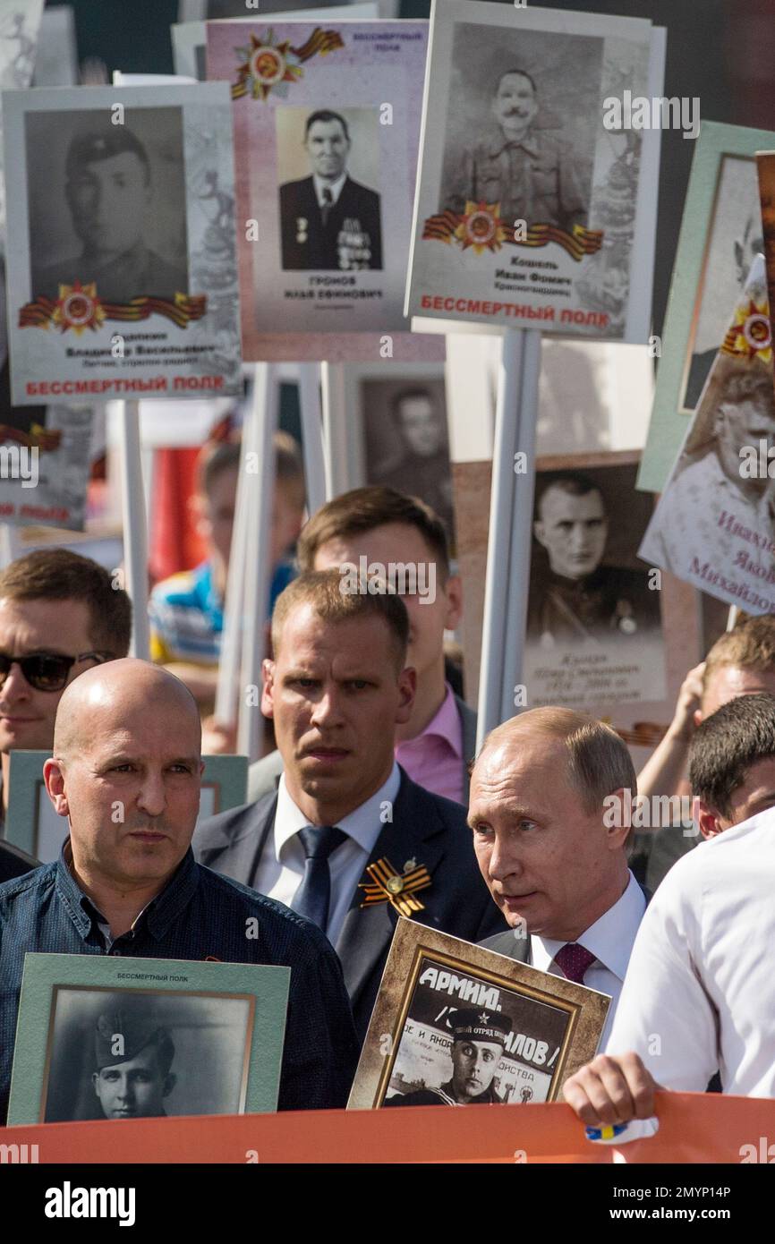 Russian President Vladimir Putin, right, holds a photograph of his ...