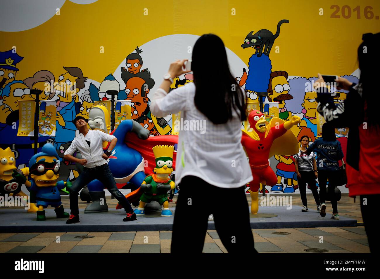 A man poses for a photo with statues of characters from the cartoon ...