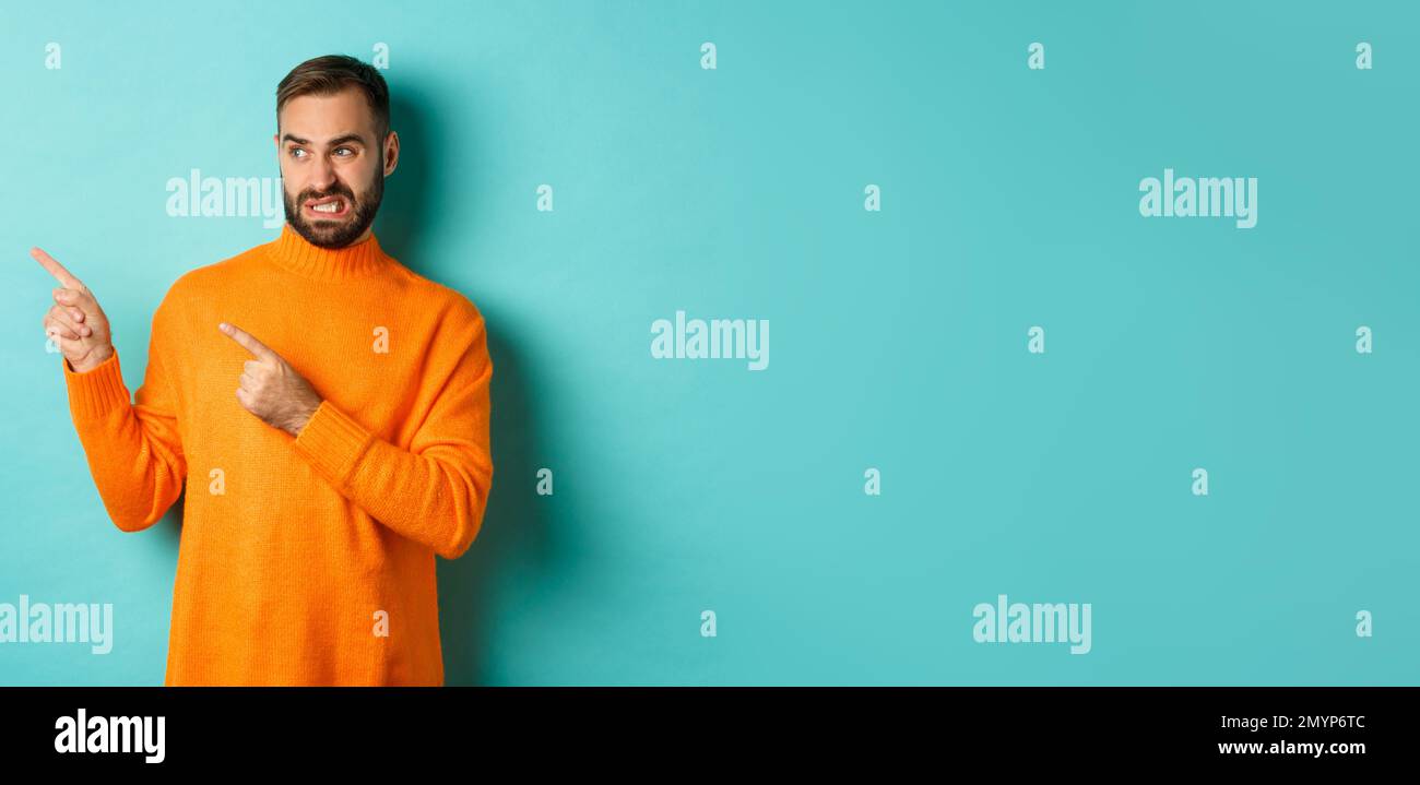 Displeased man cringe from something bad, pointing and looking at ...