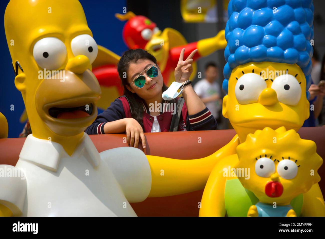 A woman poses for a photo with statues of characters from the cartoon ...
