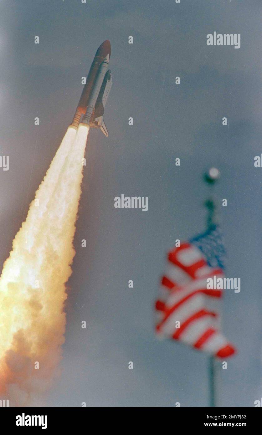 The space shuttle orbiter Discovery flies past an American flag at the ...