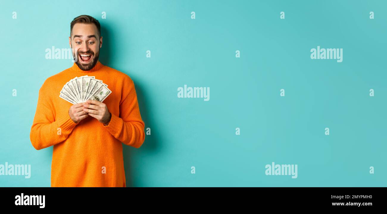 Image of man looking happy at money, smiling amazed, standing over ...