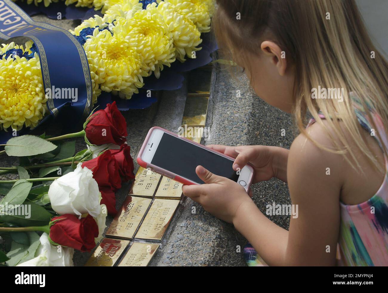 Samantha Law, 4, takes a photo of the name plaque of her late father ...