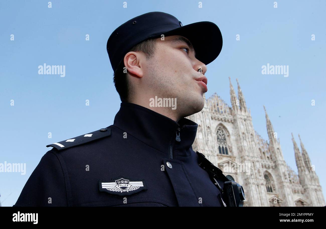 A Chinese Police officer patrols in front of Milan's gothic cathedral ...