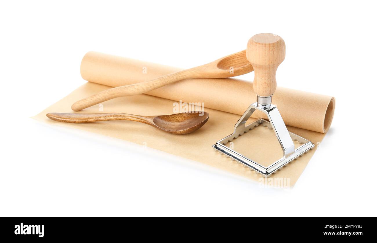 Roll of baking paper, spoons and ravioli cutter on white background ...