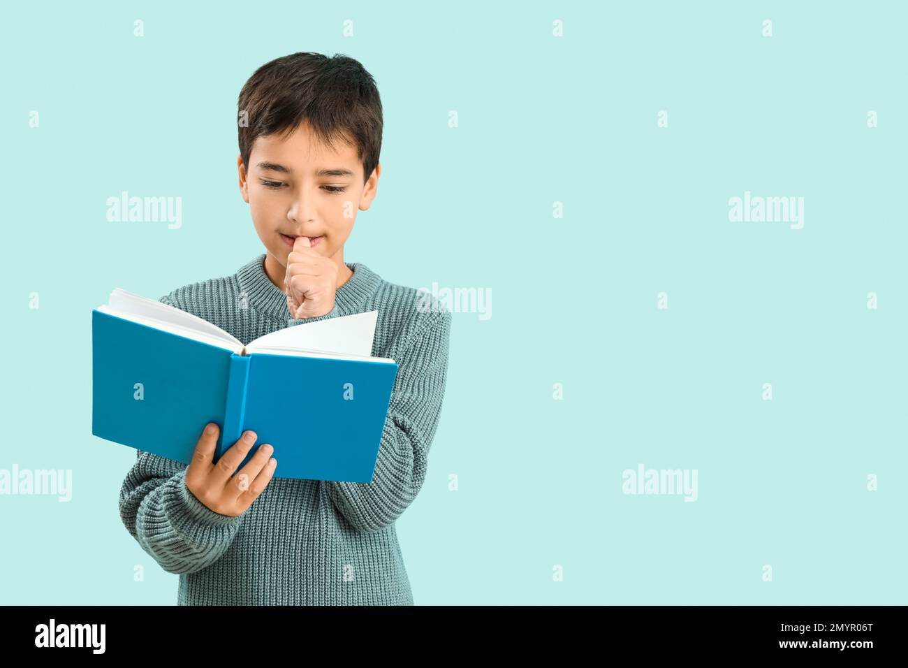 Little boy with book biting nails on blue background Stock Photo - Alamy