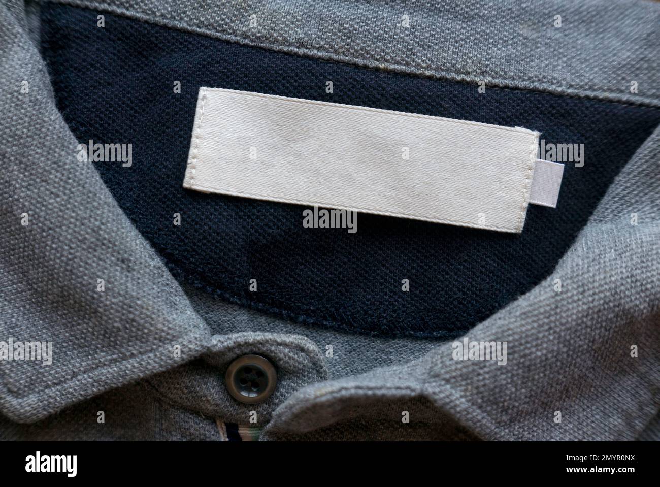 Blank white laundry care clothes label on grey fabric texture ...