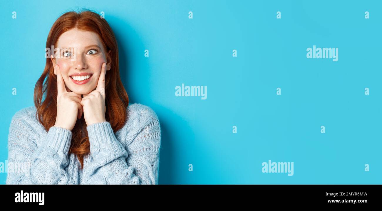Close-up of funny redhead teen girl making faces, squinting and ...