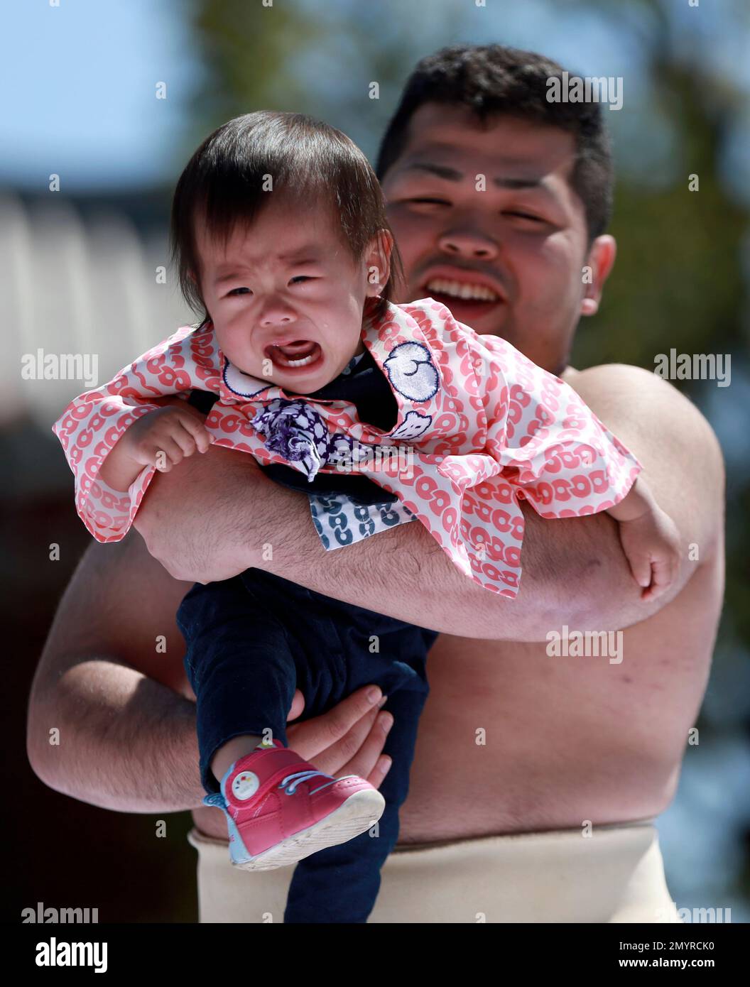 Held by a college sumo wrestler, one of babies cries in the Naki Sumo ...